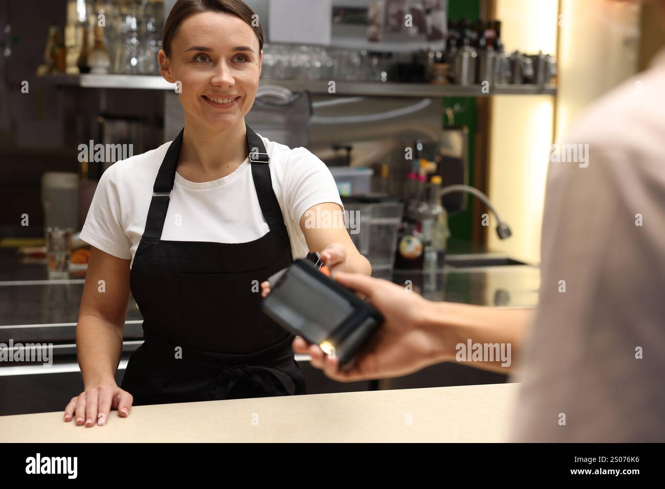 Cafe worker taking payment from client via terminal indoors Stock Photo ...