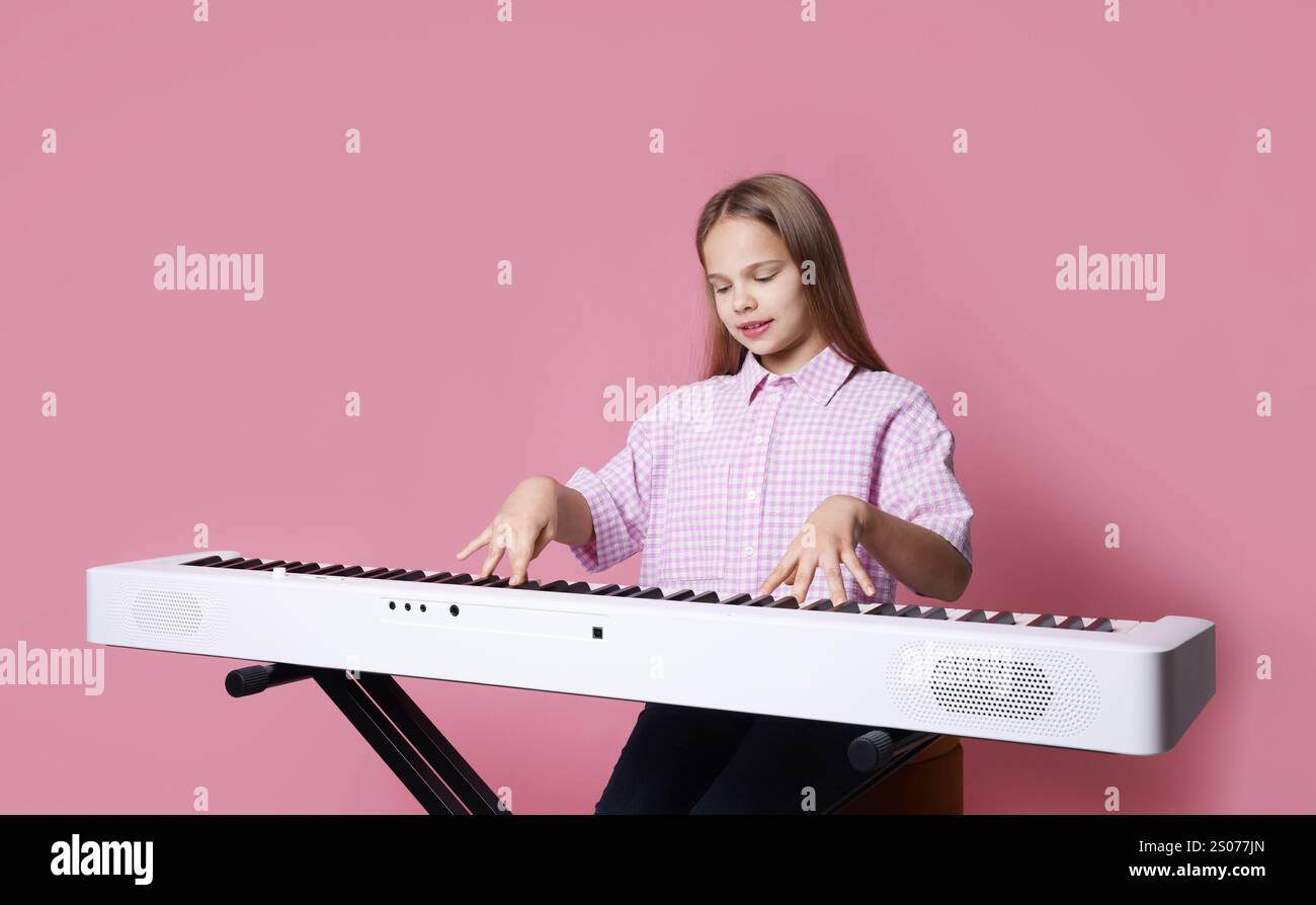 Cute girl playing synthesizer on pink background Stock Photo - Alamy
