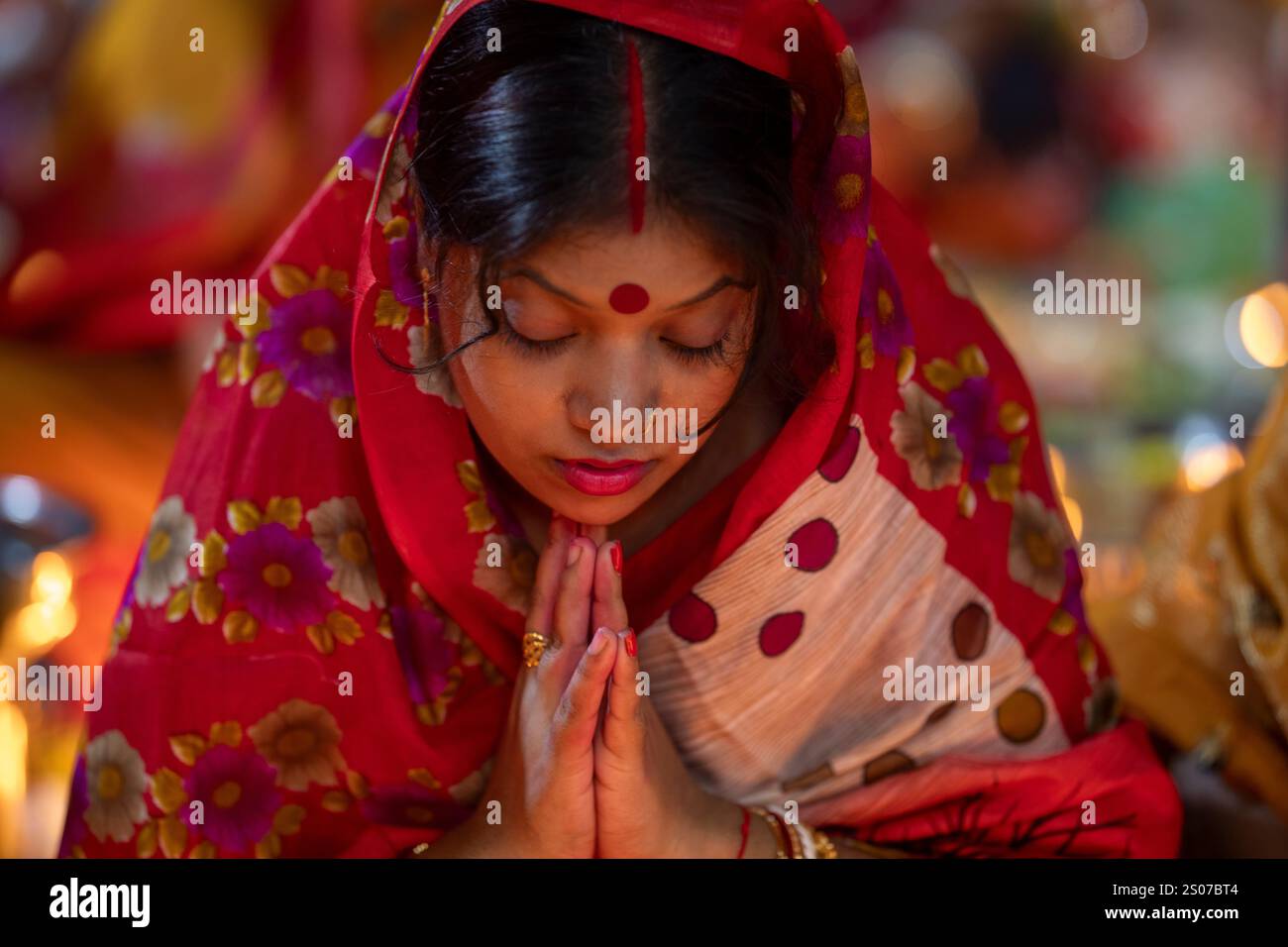A woman sits in prayer with burning incense and glowing oil lamps ...