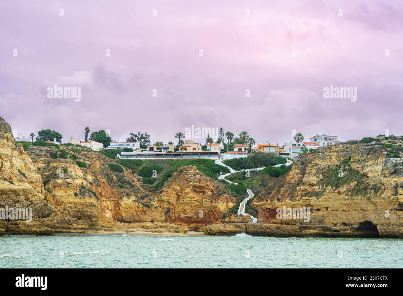 A picturesque coastal village atop rugged cliffs under a purple sunset ...