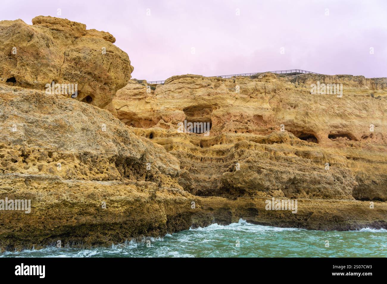 At dusk, Golden coastal cliffs rising above emerald waters with ...
