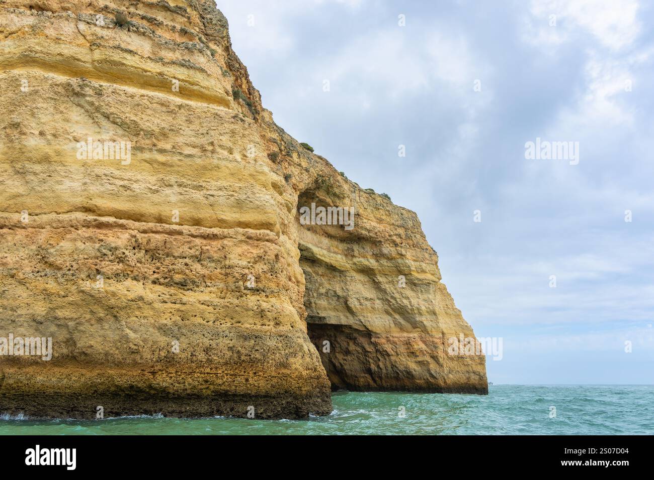 At dusk, Golden coastal cliffs rising above emerald waters with ...