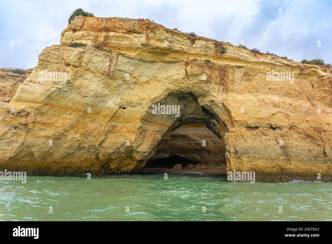 At dusk, Golden coastal cliffs rising above emerald waters with ...
