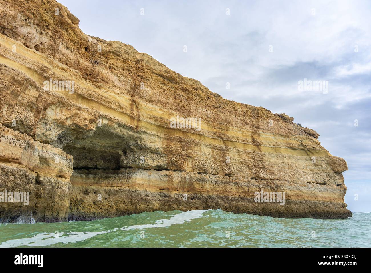 At dusk, Golden coastal cliffs rising above emerald waters with ...