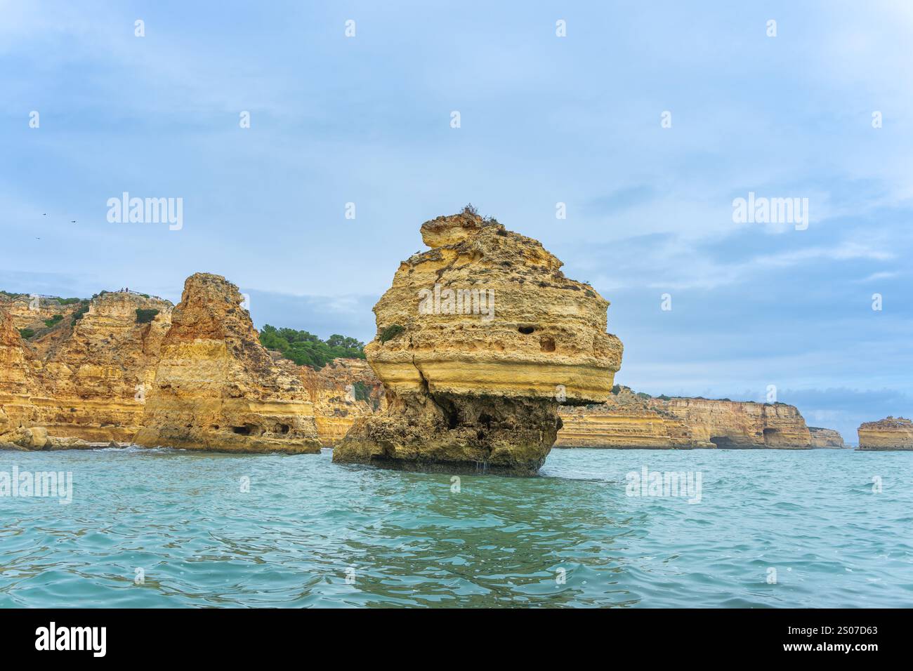 At dusk, Golden coastal cliffs rising above emerald waters with ...