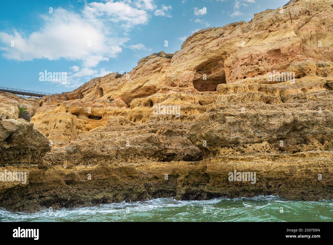 At dusk, Golden coastal cliffs rising above emerald waters with ...