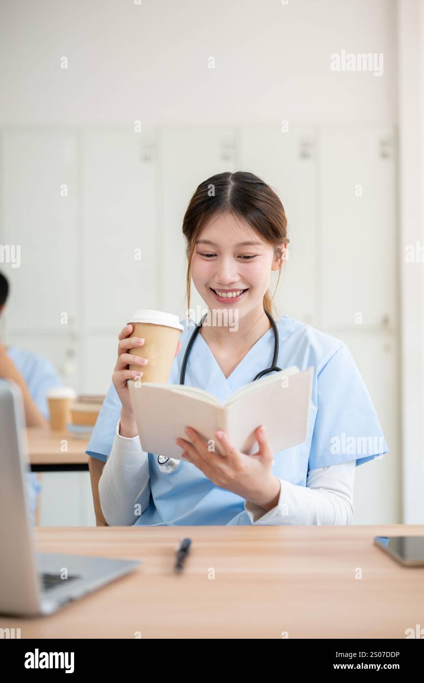 A lovely, charming Asian female medical student in scrubs is sipping a ...