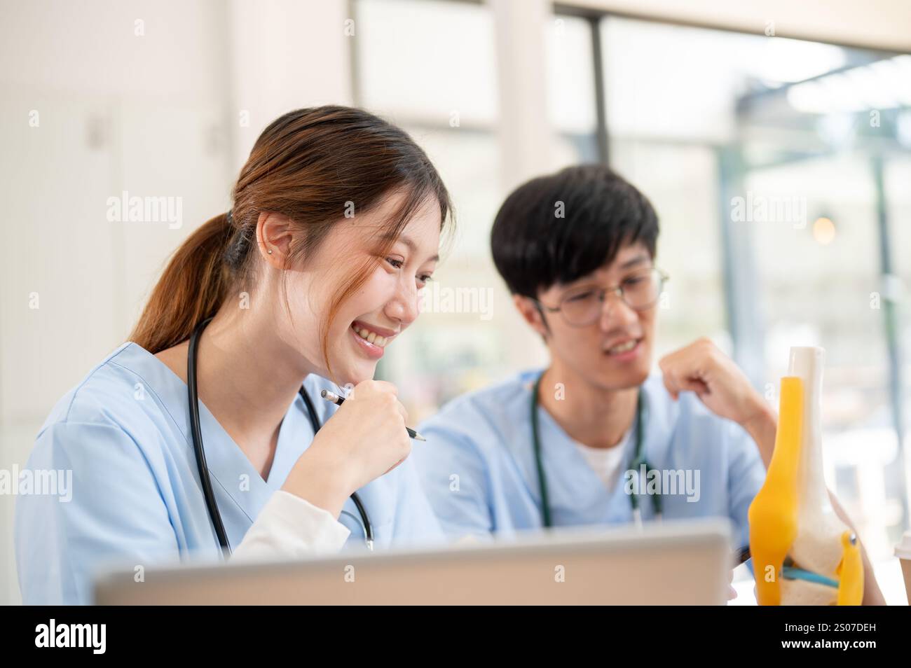 A beautiful, smart Asian female medical student in scrubs is examining ...