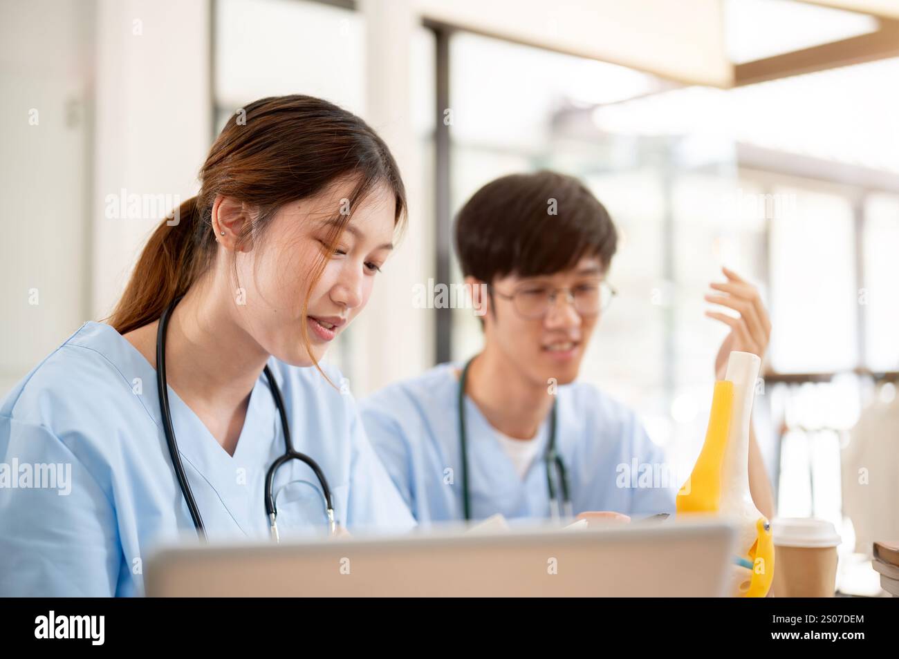 A beautiful, smart Asian female medical student in scrubs is examining ...