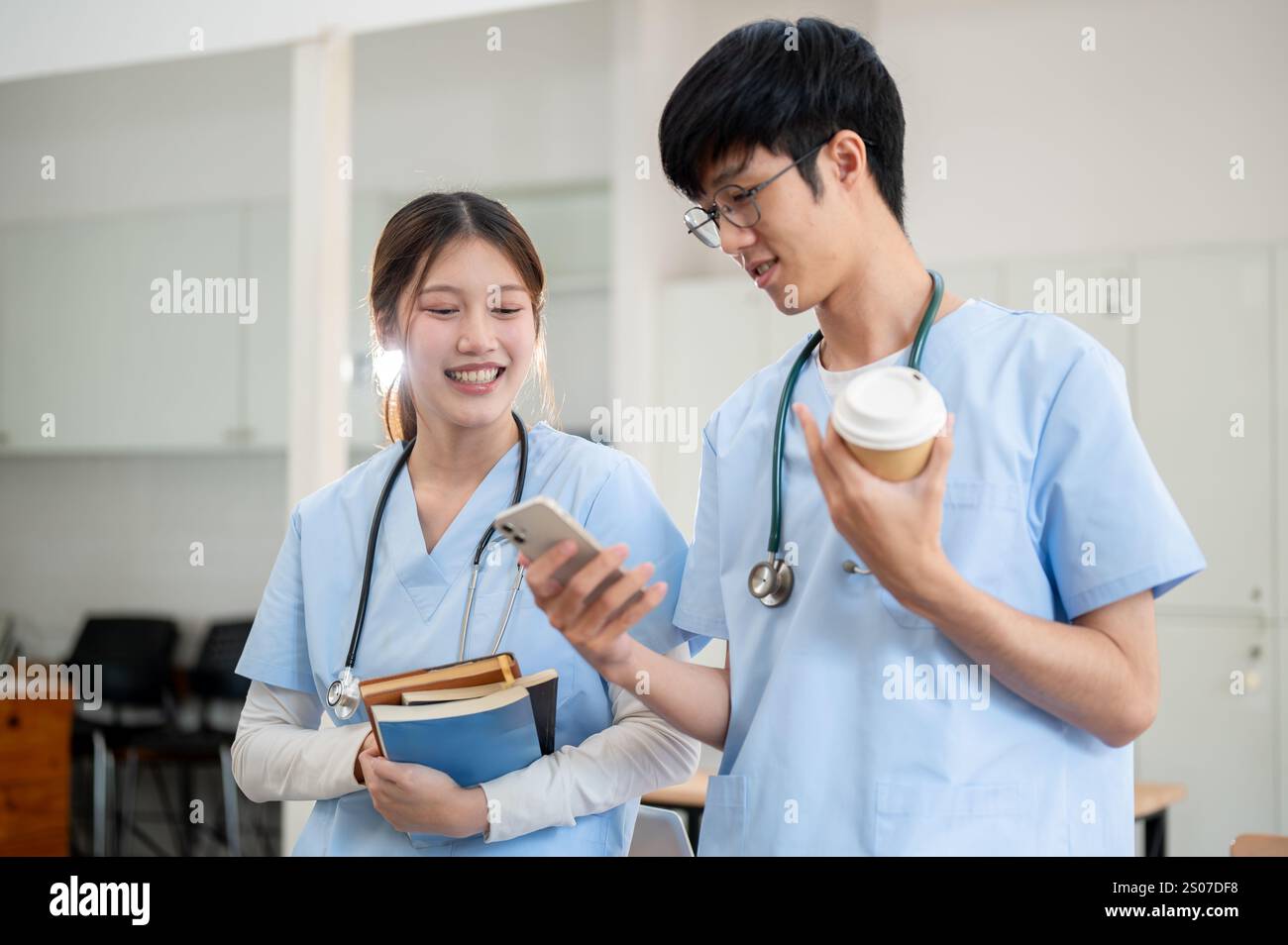 Two happy Asian medical students in scrubs are standing in their ...