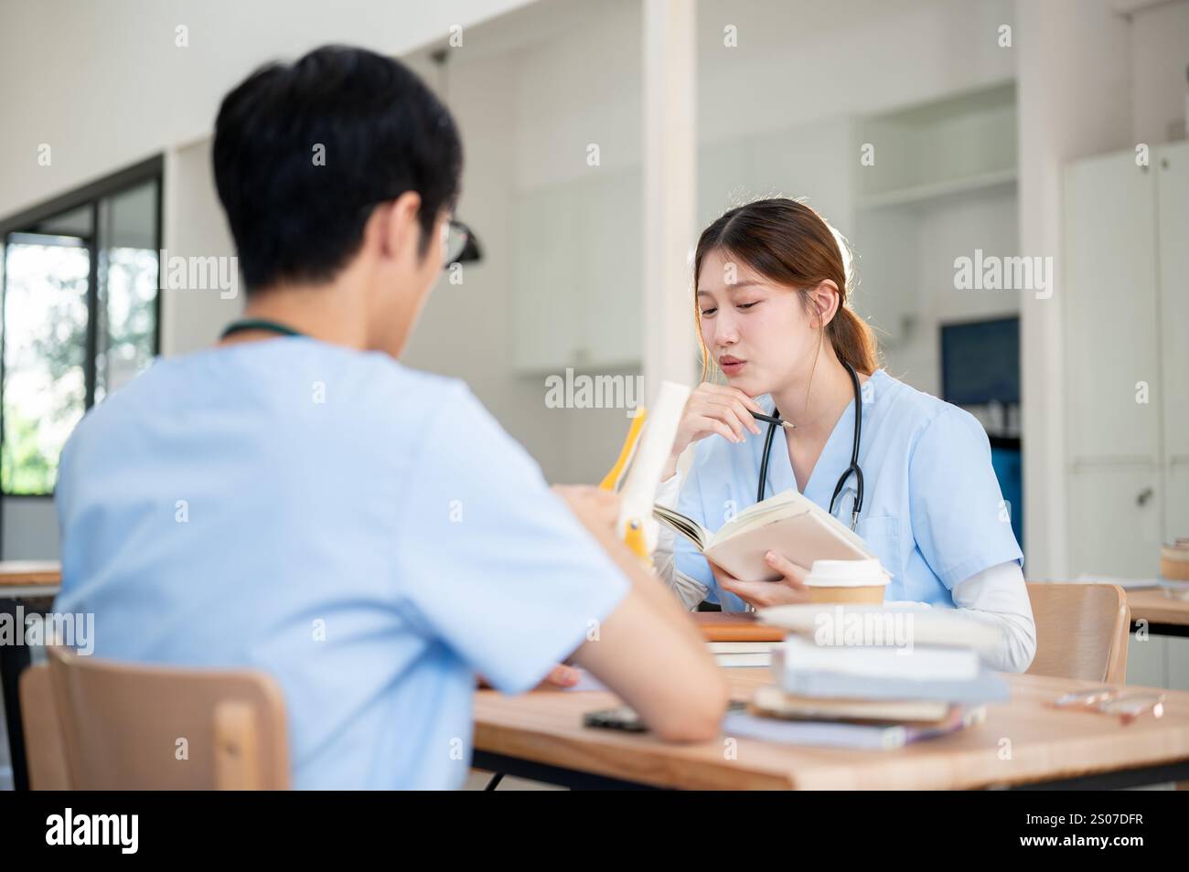 A positive, smiling Asian female medical student in scrubs is studying ...