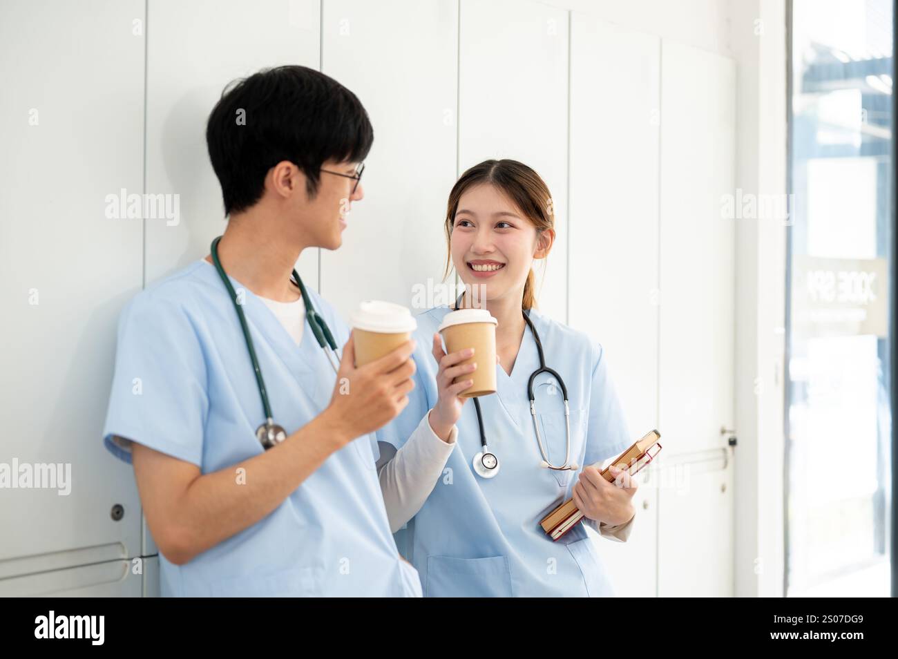Two happy Asian male and female doctors are flirting, enjoying a ...