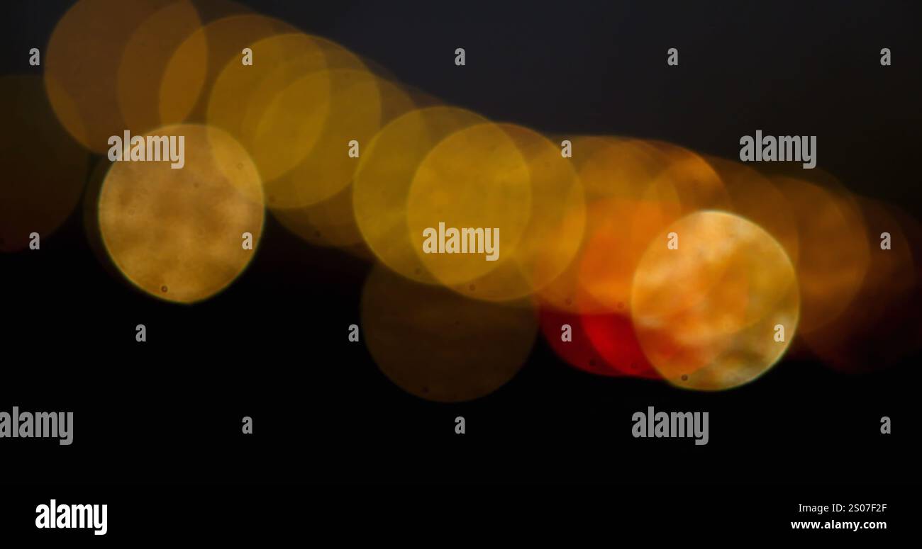 Digital image of glowing golden spots of light moving against black ...