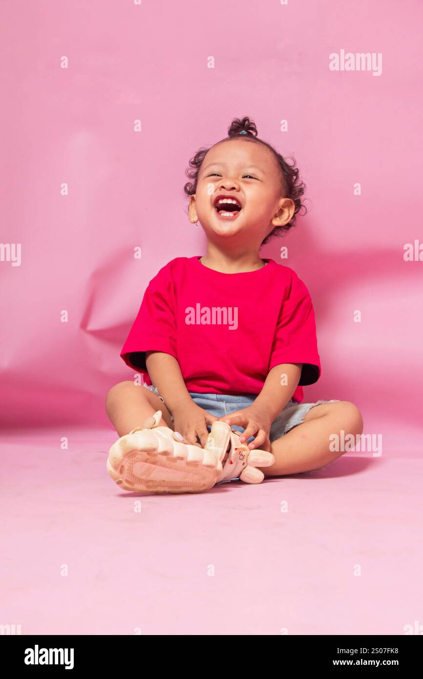 portrait of eight month old baby girl sitting with cheerful laughter ...