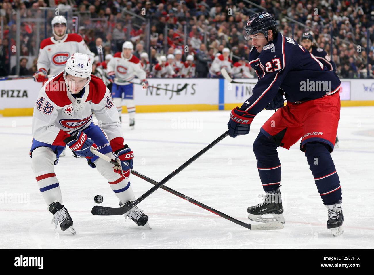 Columbus Blue Jackets defenseman Sean Monahan, right, passes the puck ...