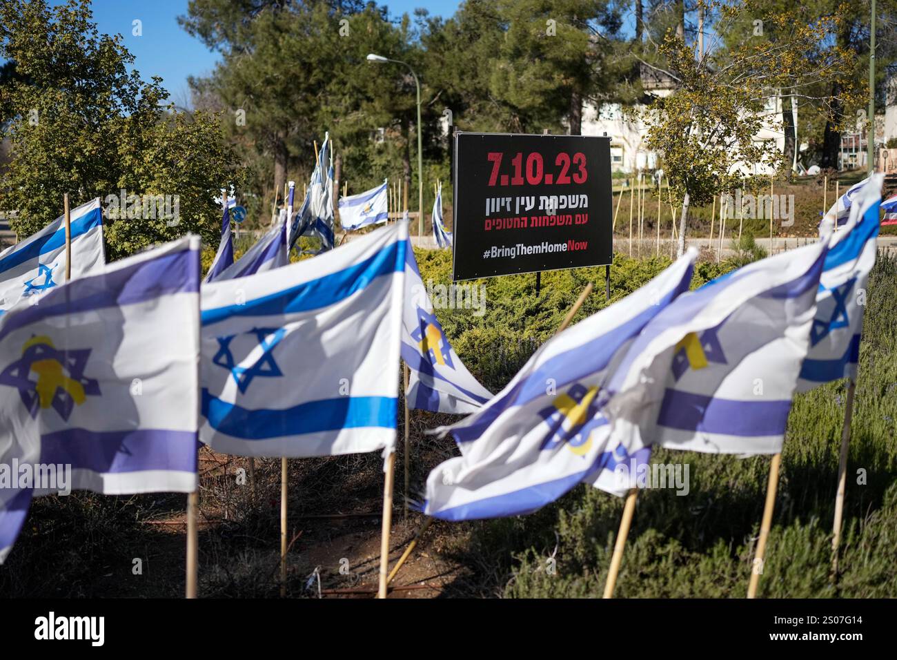 Israeli flags fly next to a sign in Hebrew that reads, "The families of ...