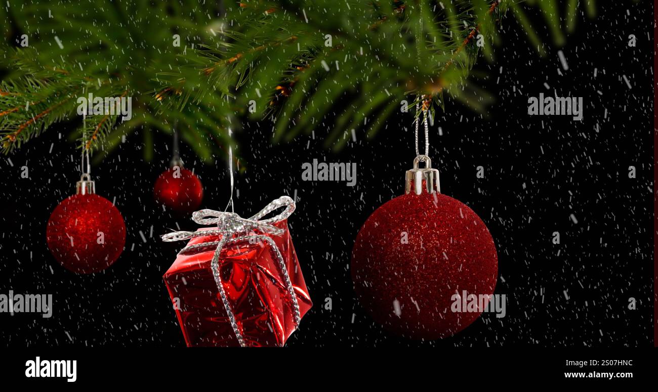 Image of snow falling over hanging baubles and christmas gifts on a ...