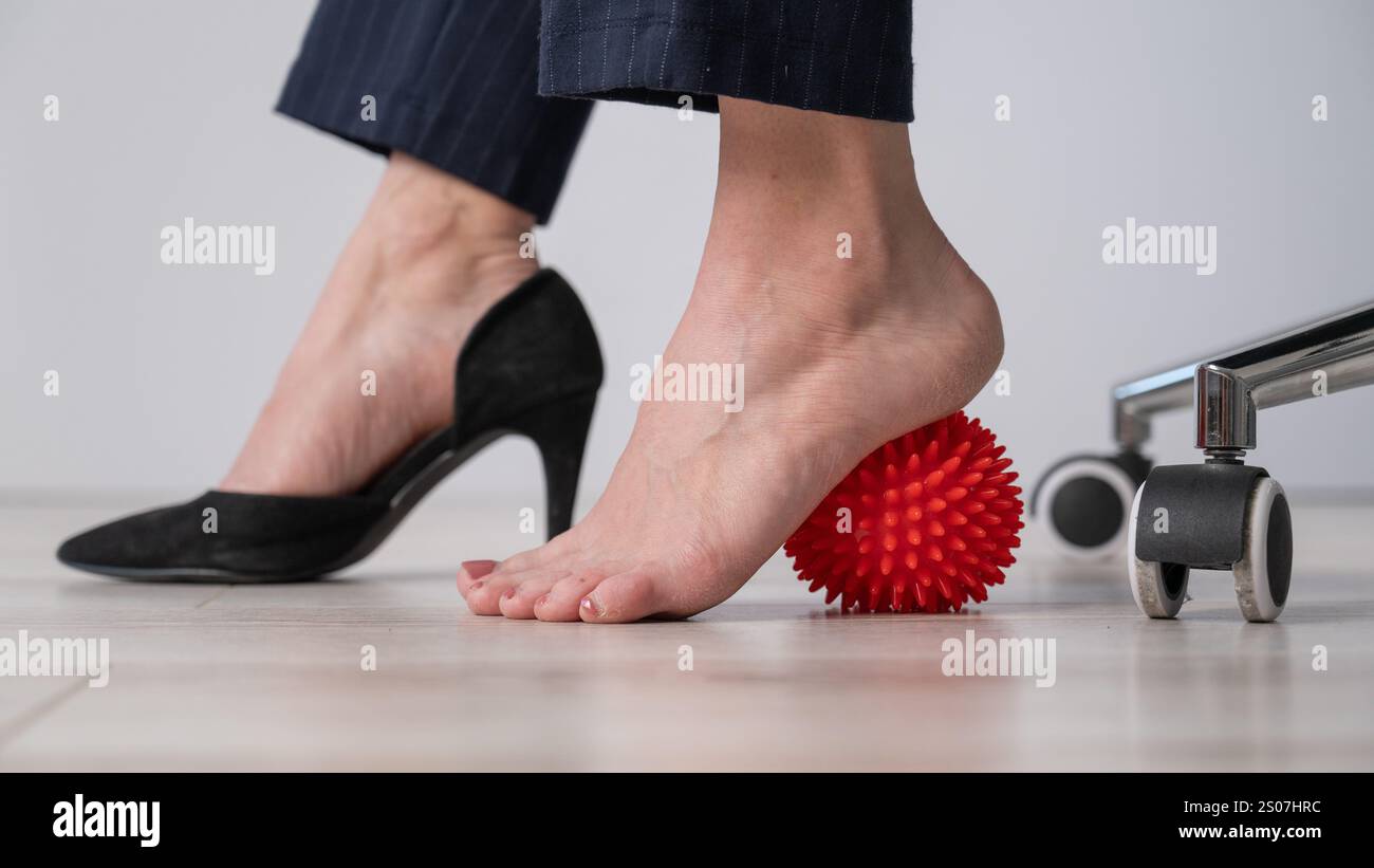 Business woman massages her feet on a massage ball with spikes Stock ...