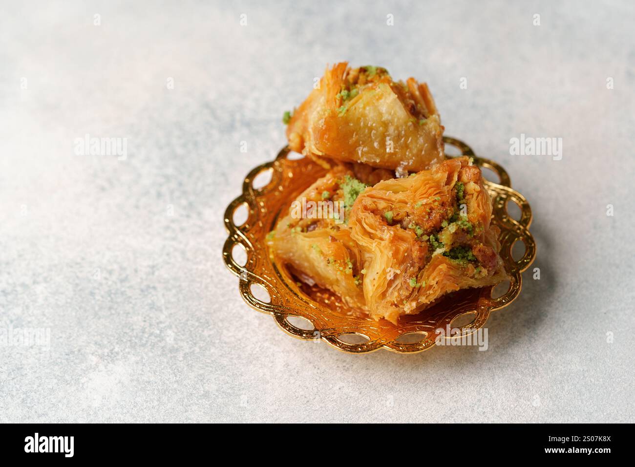 Sweet and flaky baklava served on a decorative gold plate with layers ...