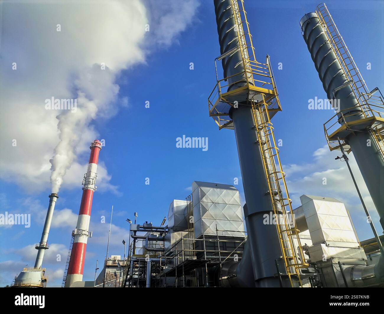 A large factory with thick smoke billowing out from its tall chimneys ...