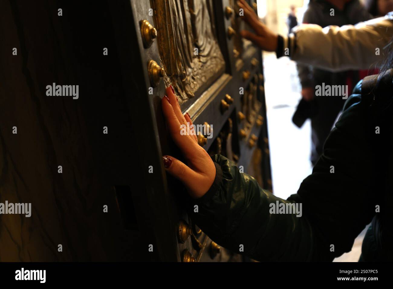 Vatican City, Italy 25.12.2024 : Pilgrims hand touch the Holy Door on ...