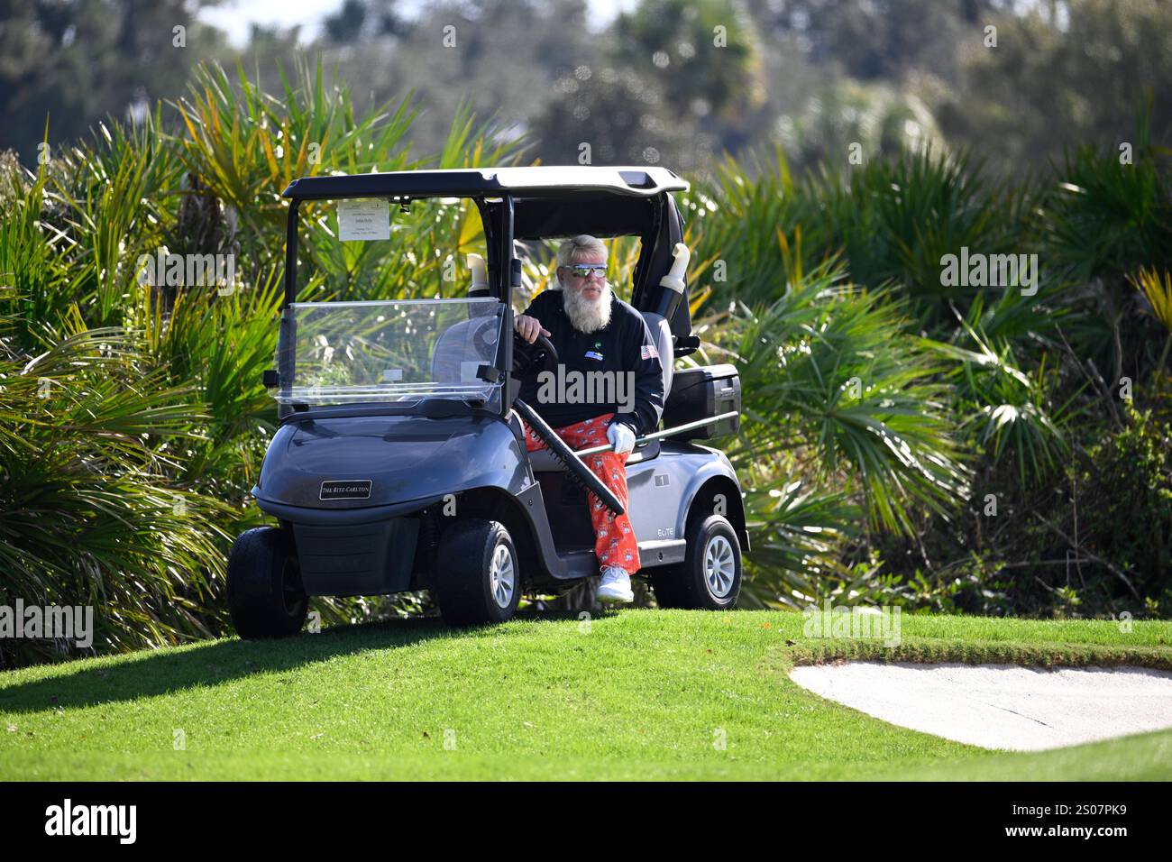 John Daly drives a cart to the third green during the first round of ...