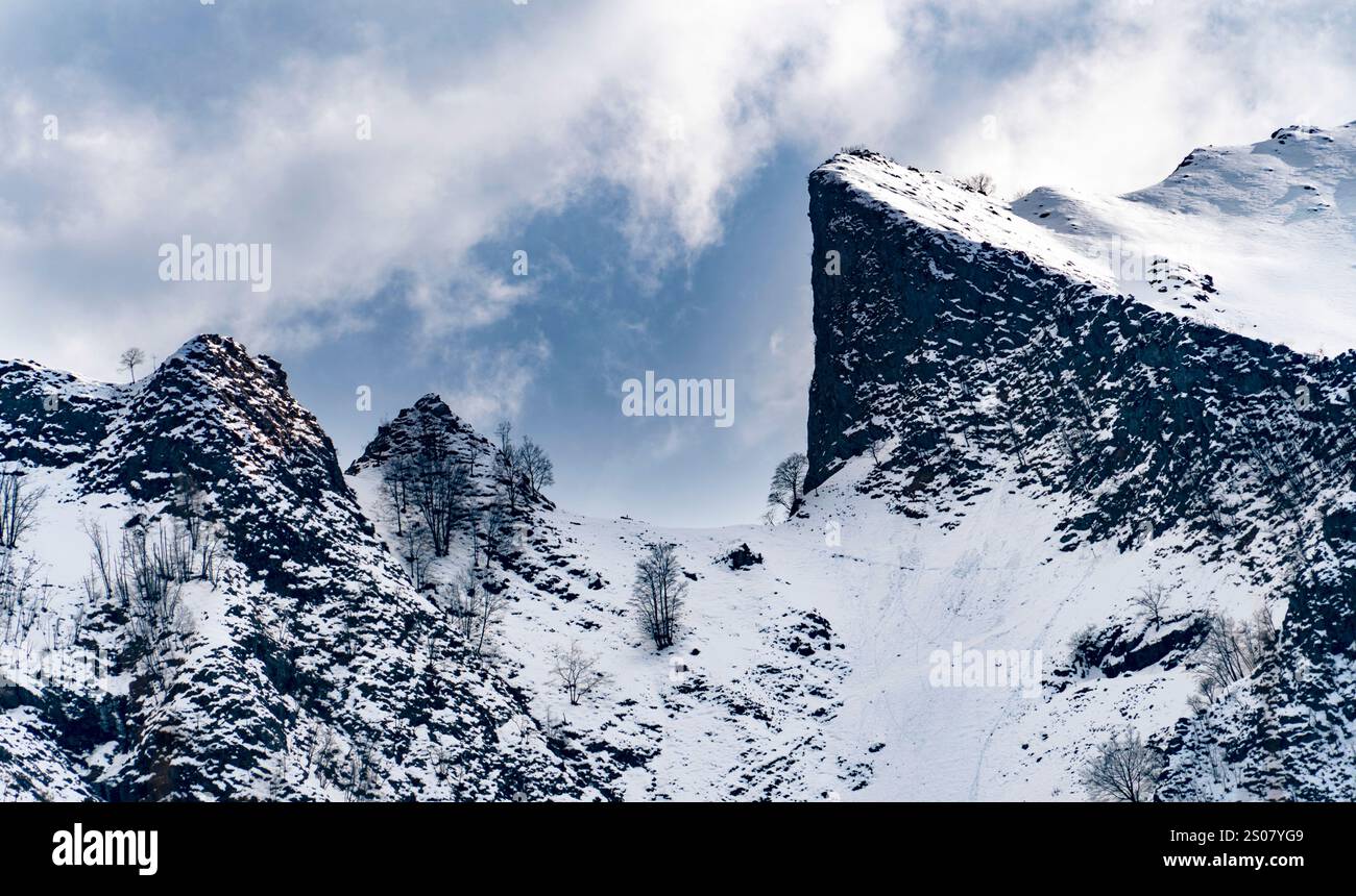 A dramatic mountain landscape featuring snow-covered peaks under a ...
