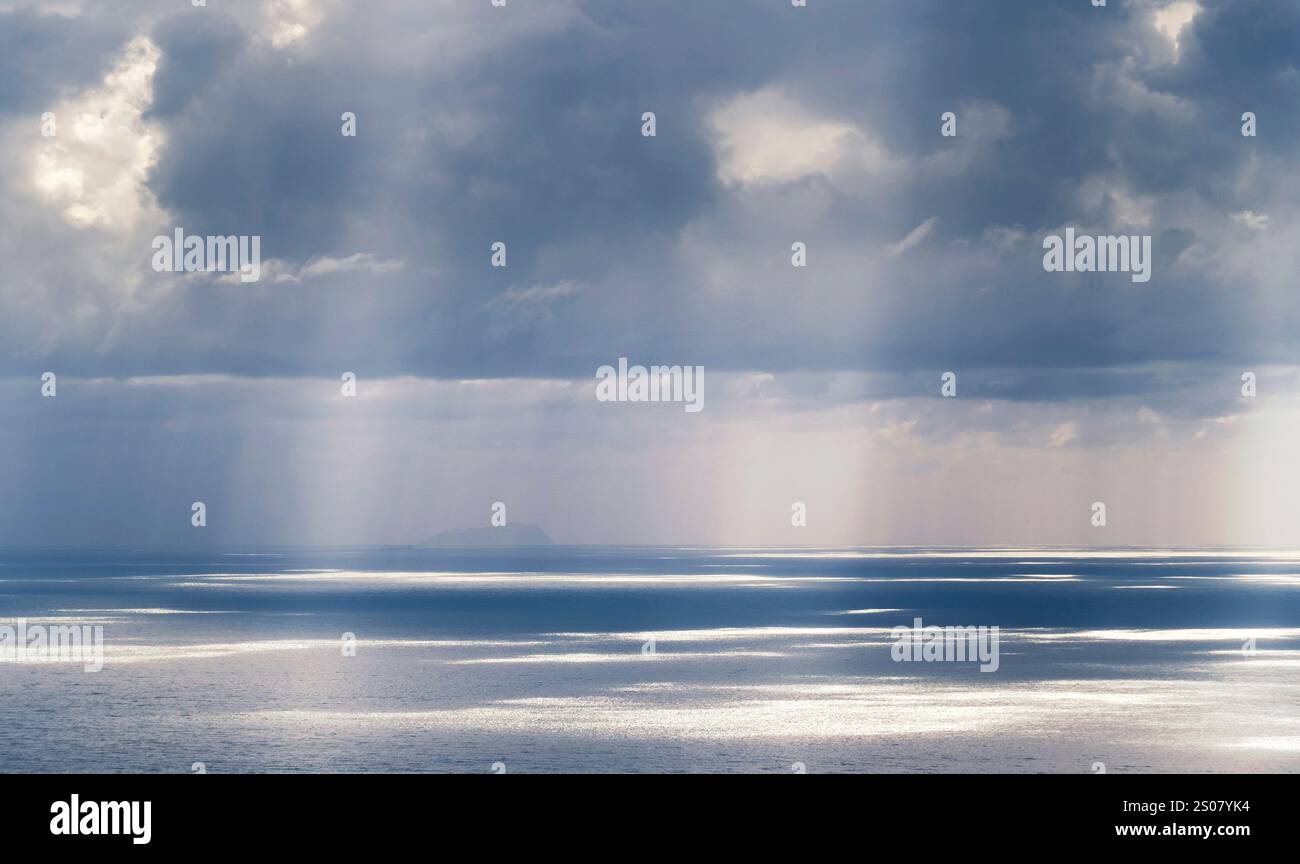 A serene seascape featuring calm waters reflecting sunlight, with ...