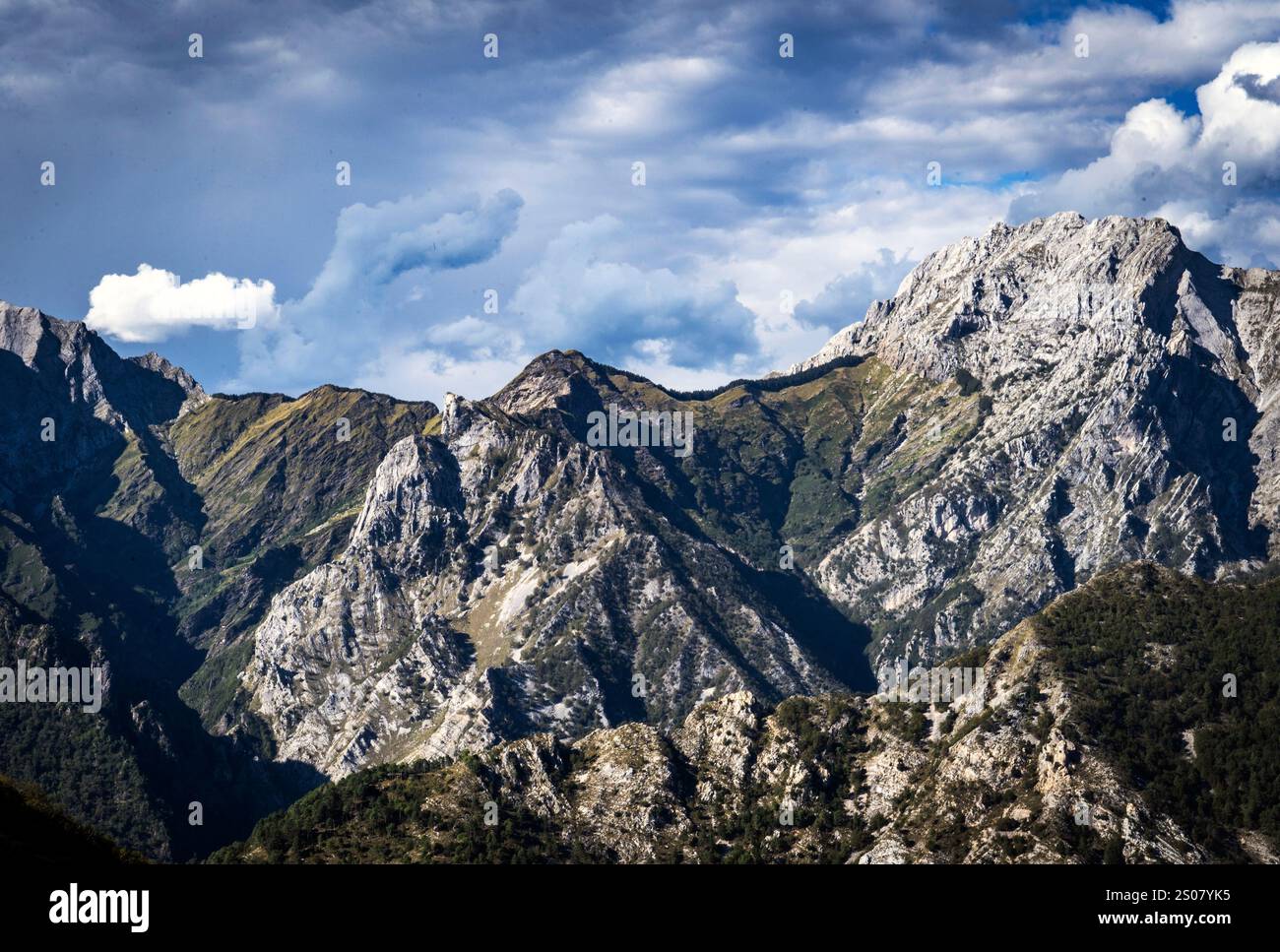 A breathtaking view of rugged mountains under a dramatic sky with clouds. The peaks are steep ...