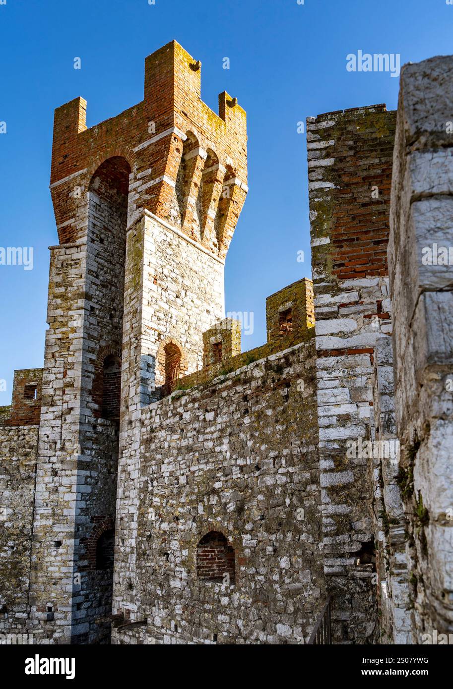 A historic stone castle with a tall brick tower against a clear blue ...