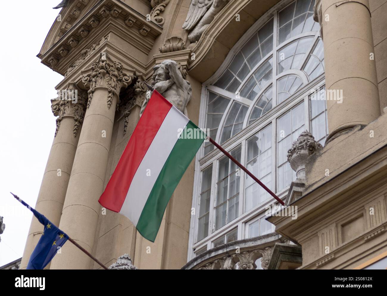 A close-up of the Hungarian flag waving alongside an EU flag on a historic building in Budapest ...