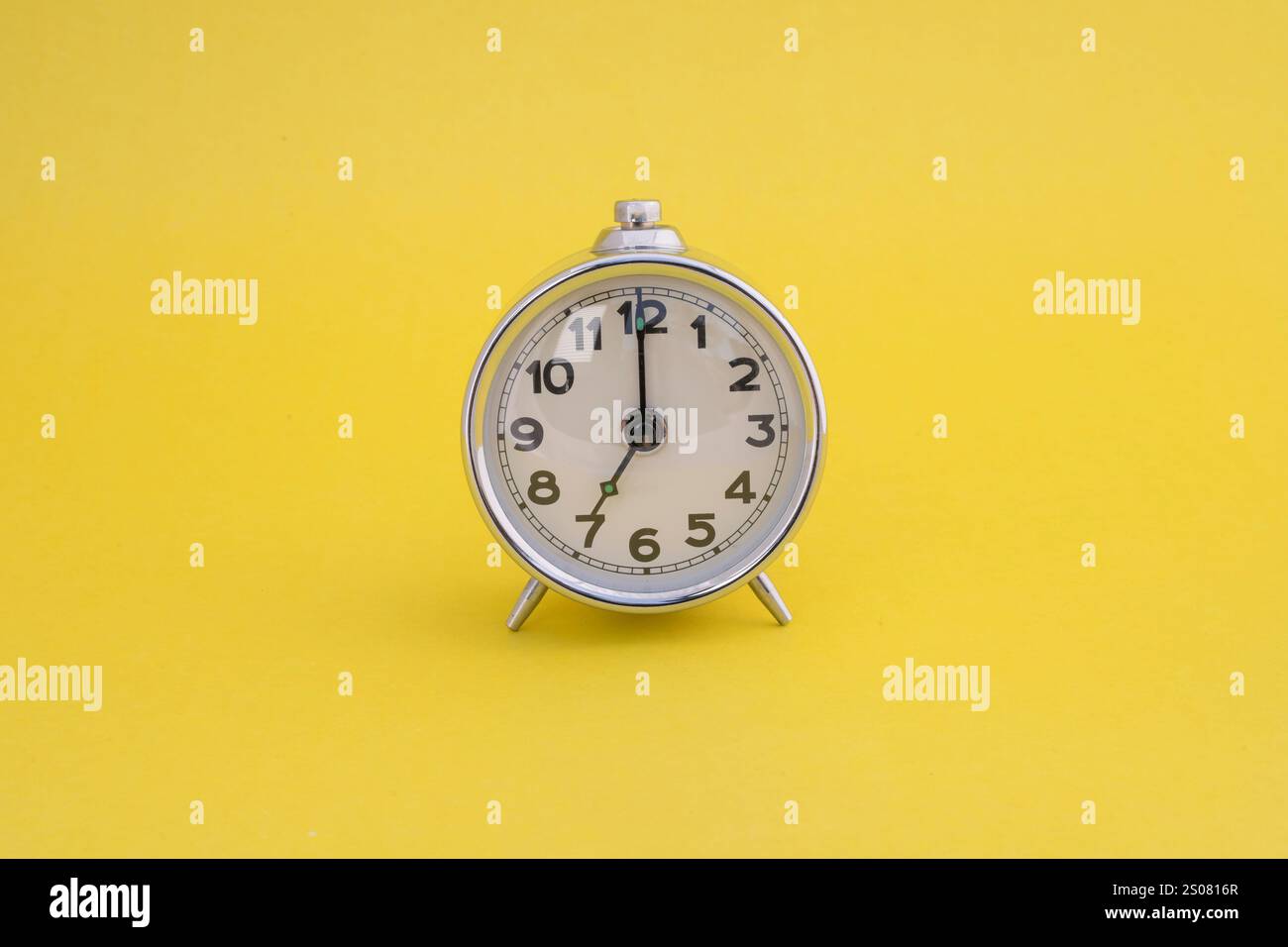 Analog alarm clock on yellow background. 7.00 am wake up time. 7:00 pm ...