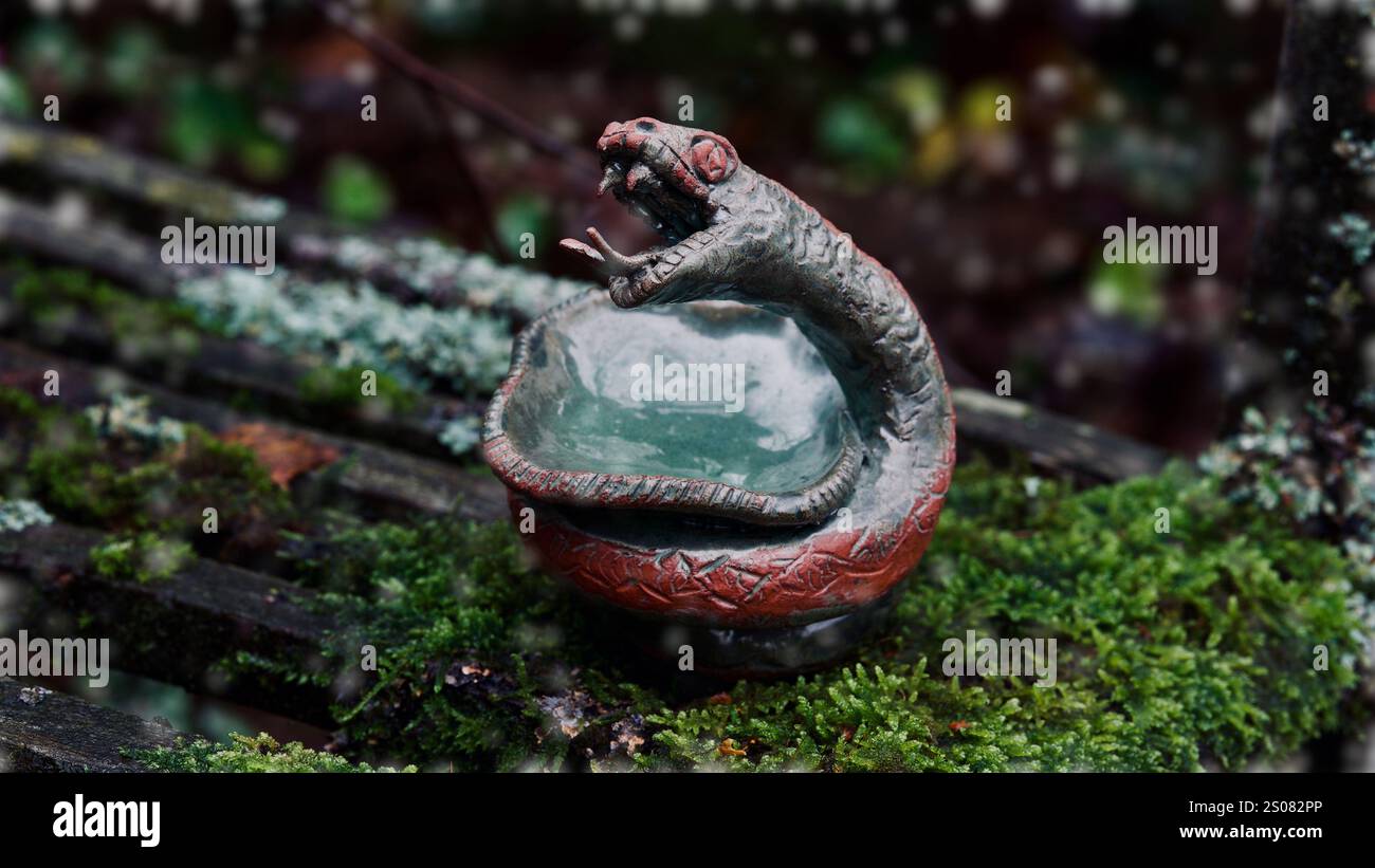 A clay snake on mossy wood. Crafting Stock Photo - Alamy