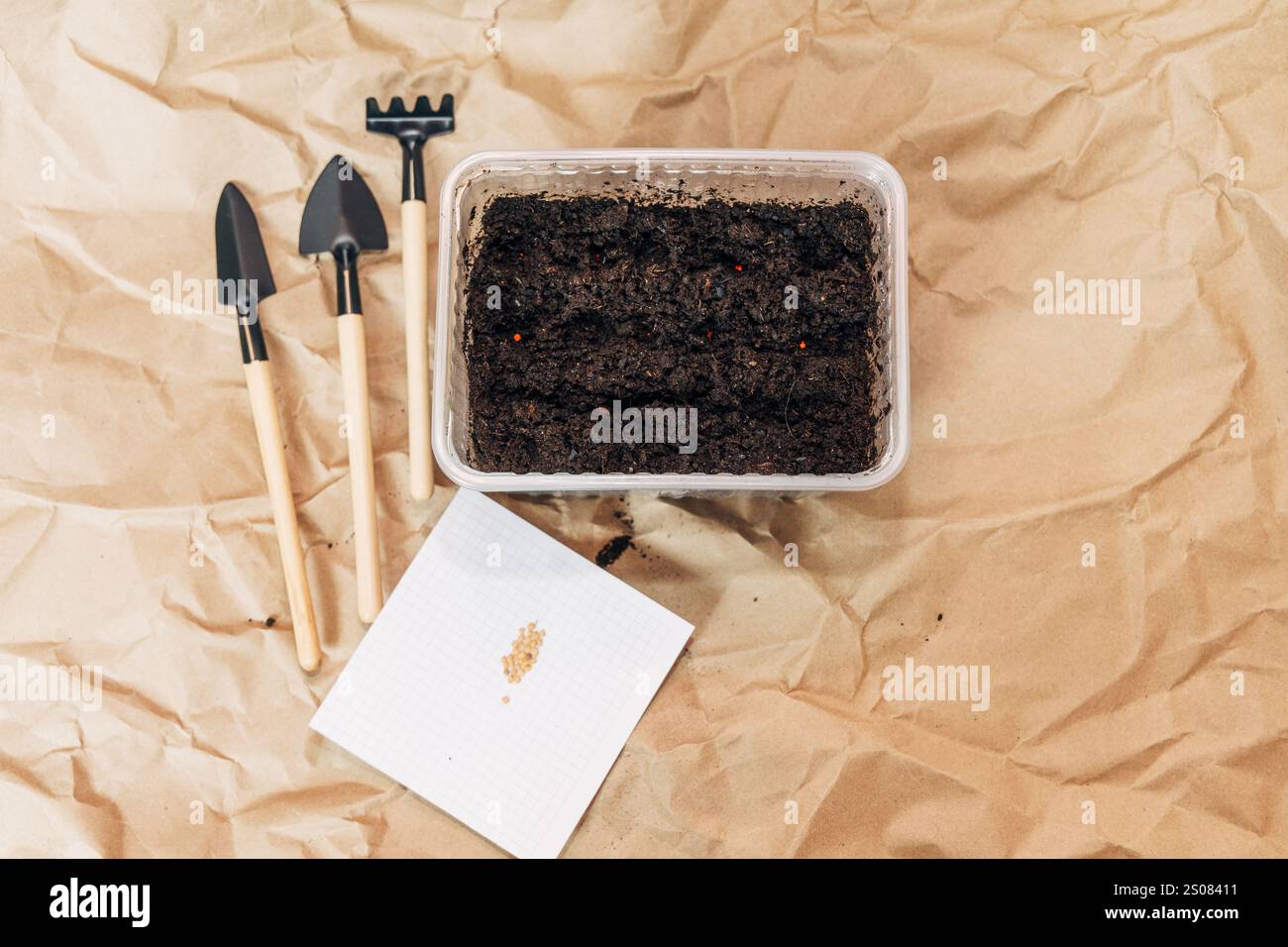 Kraft paper background, fertile soil and garden tools on top, top view ...