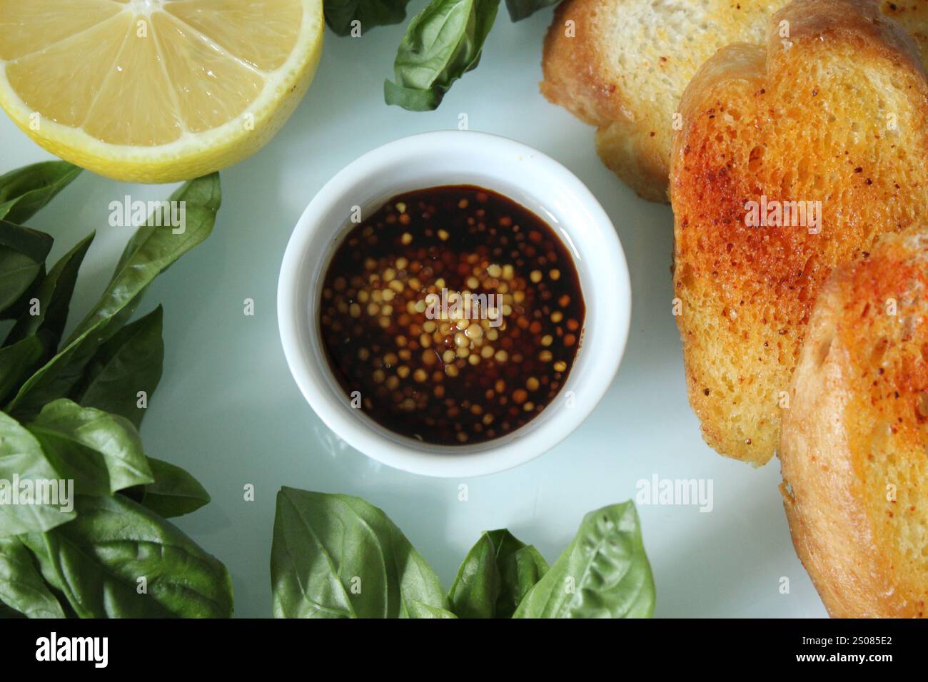 French mustard with toasted bread, basil and lemon slice on light green ...