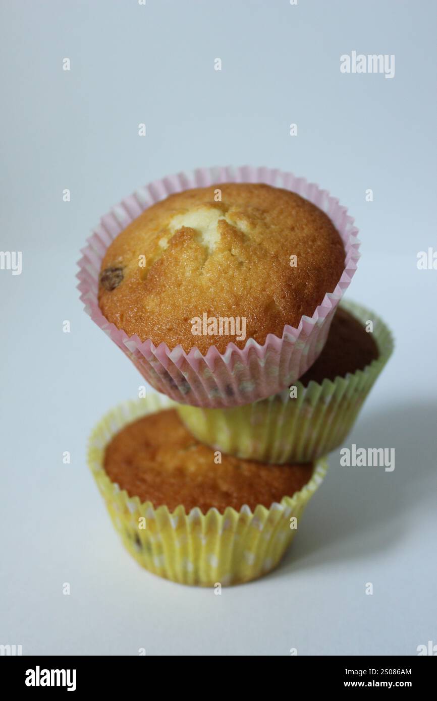 Delicious stack of three golden cupcakes balancing on white background ...