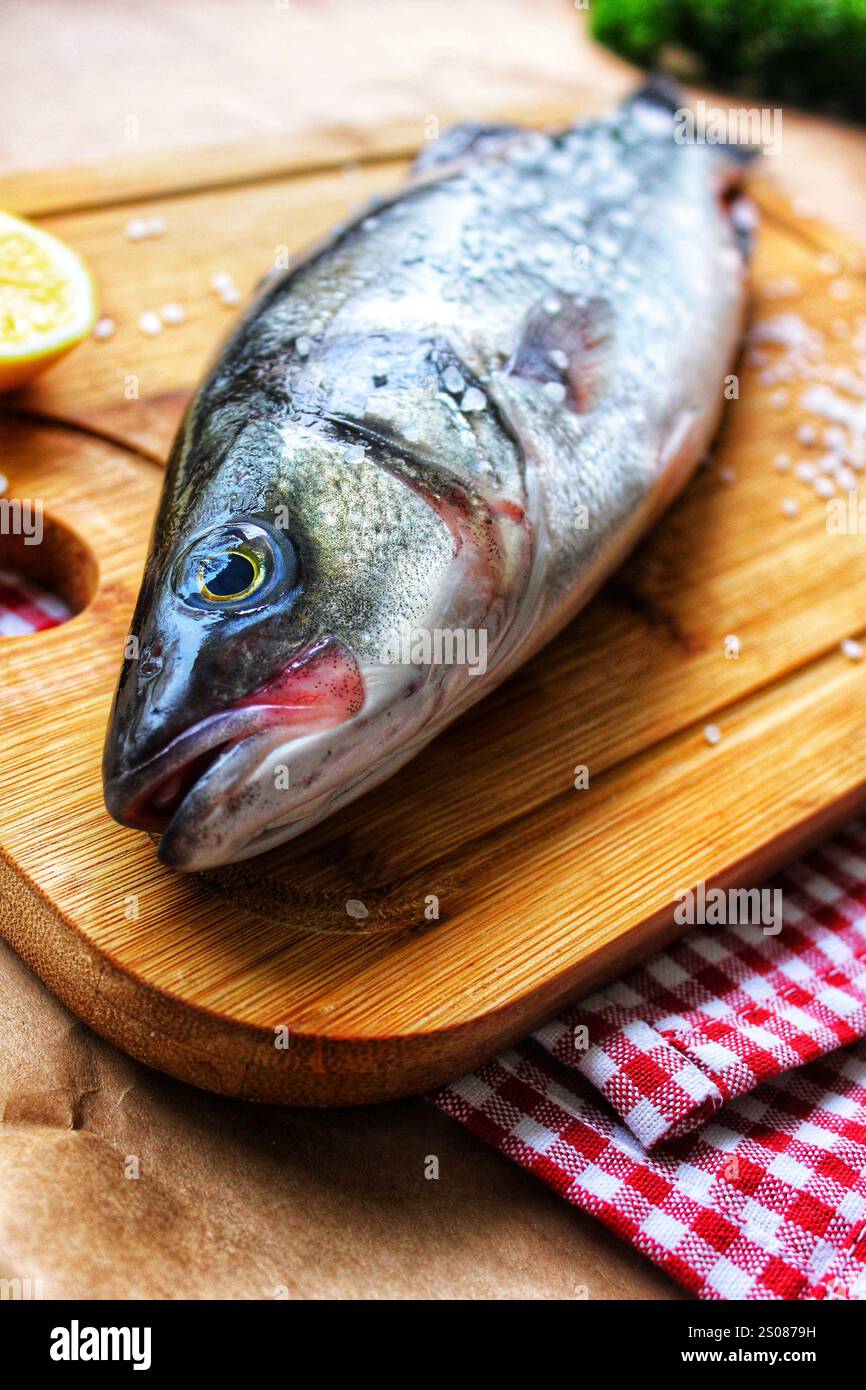 Raw sea bass seasoned with salt, accompanied by a lemon slice, ready ...