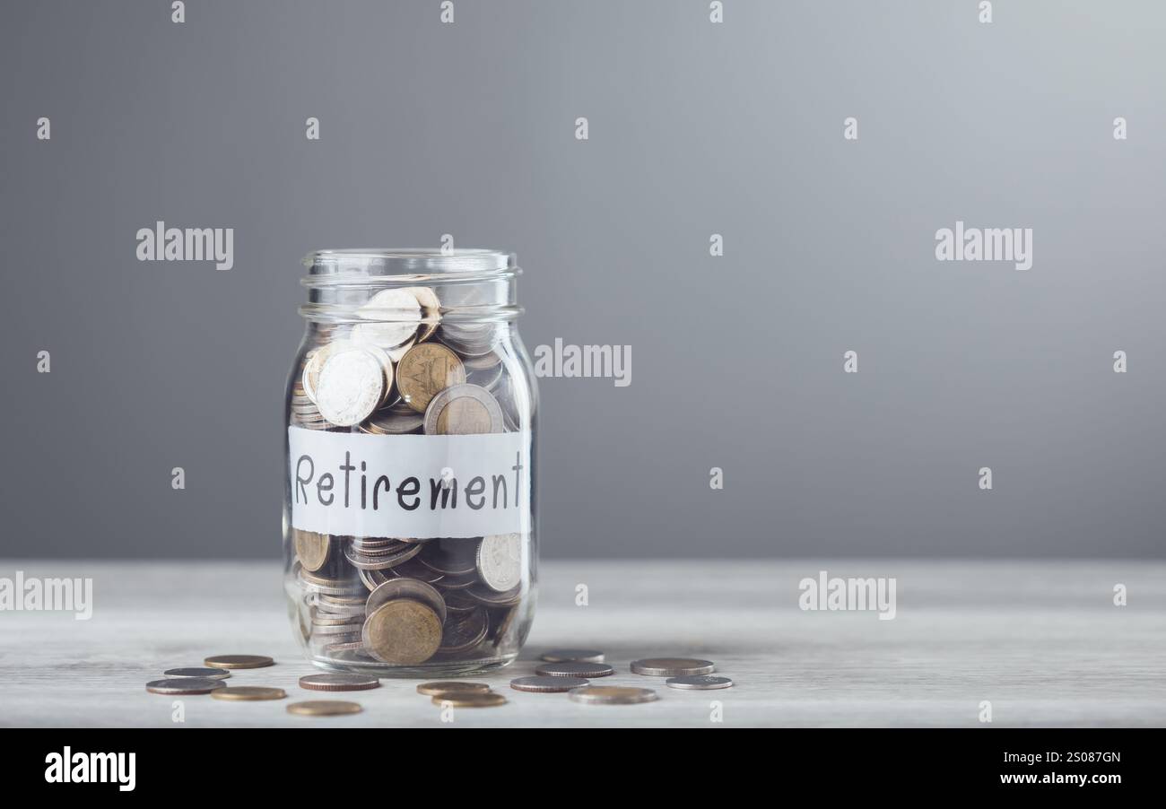 A glass jar filled with coins and a sprout labeled 'Retirement,' placed ...