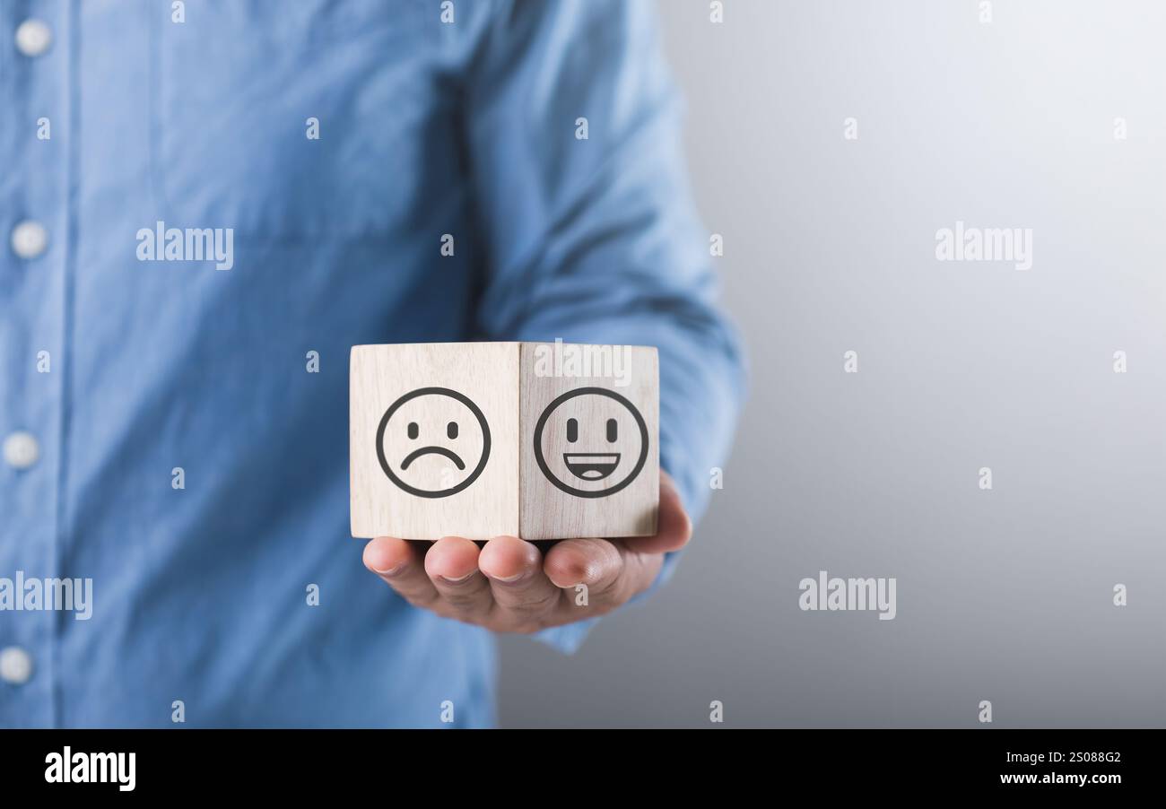 Man holds a wooden block with a smiling face, symbolizing positivity ...