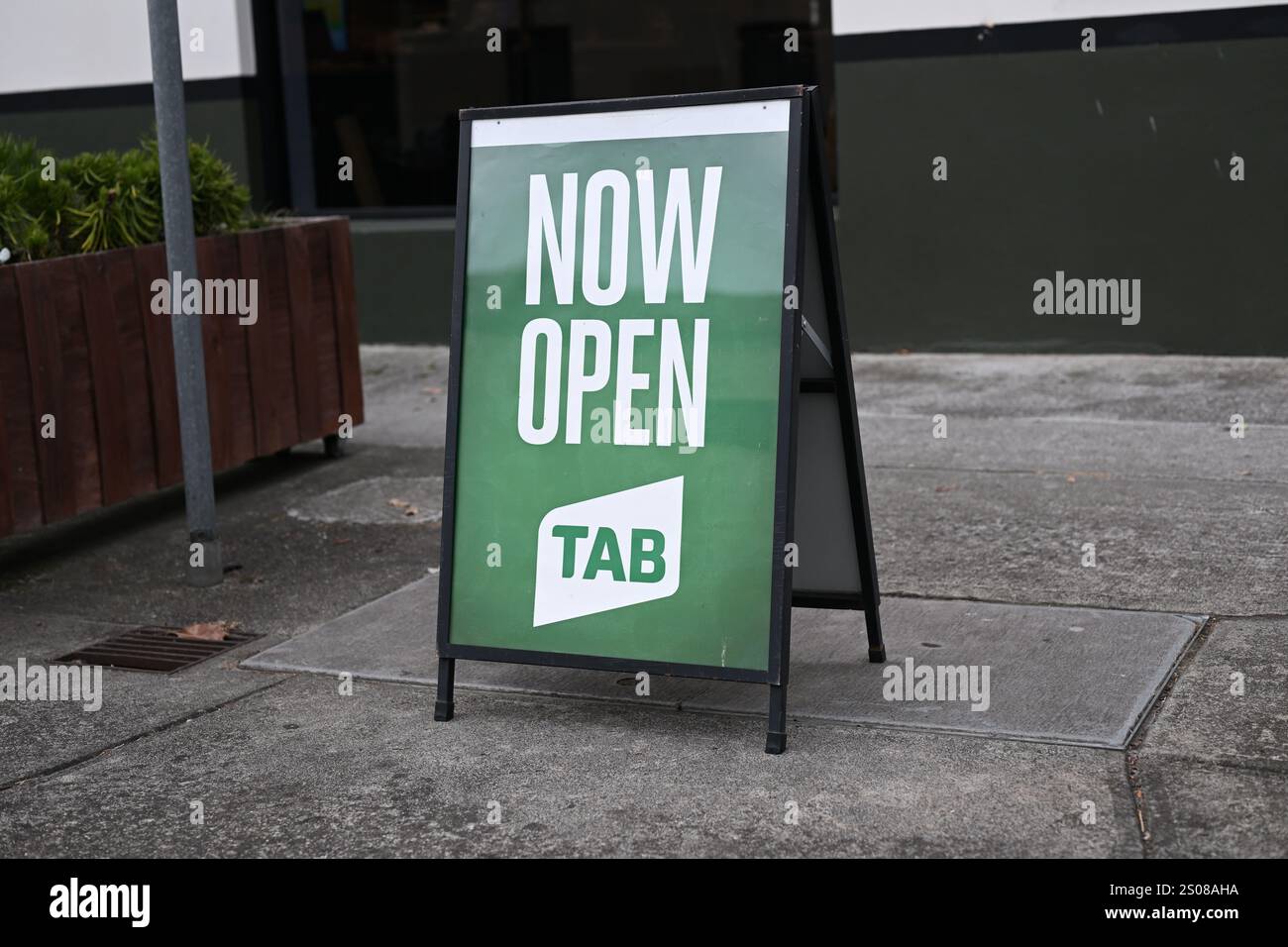 Green now open TAB sign on a footpath, outside an establishment where ...