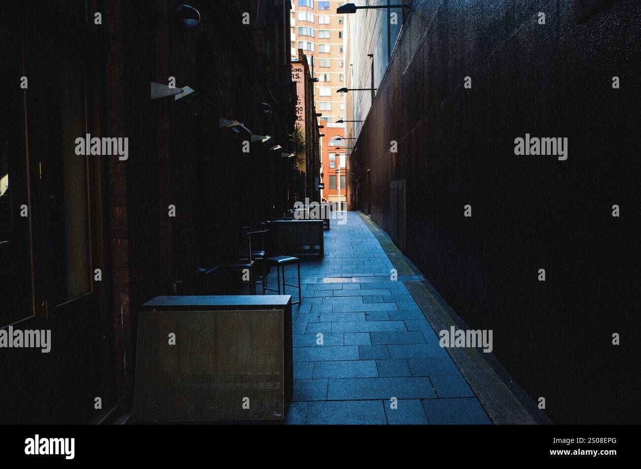 A narrow urban alleyway with dim lighting and scattered outdoor ...