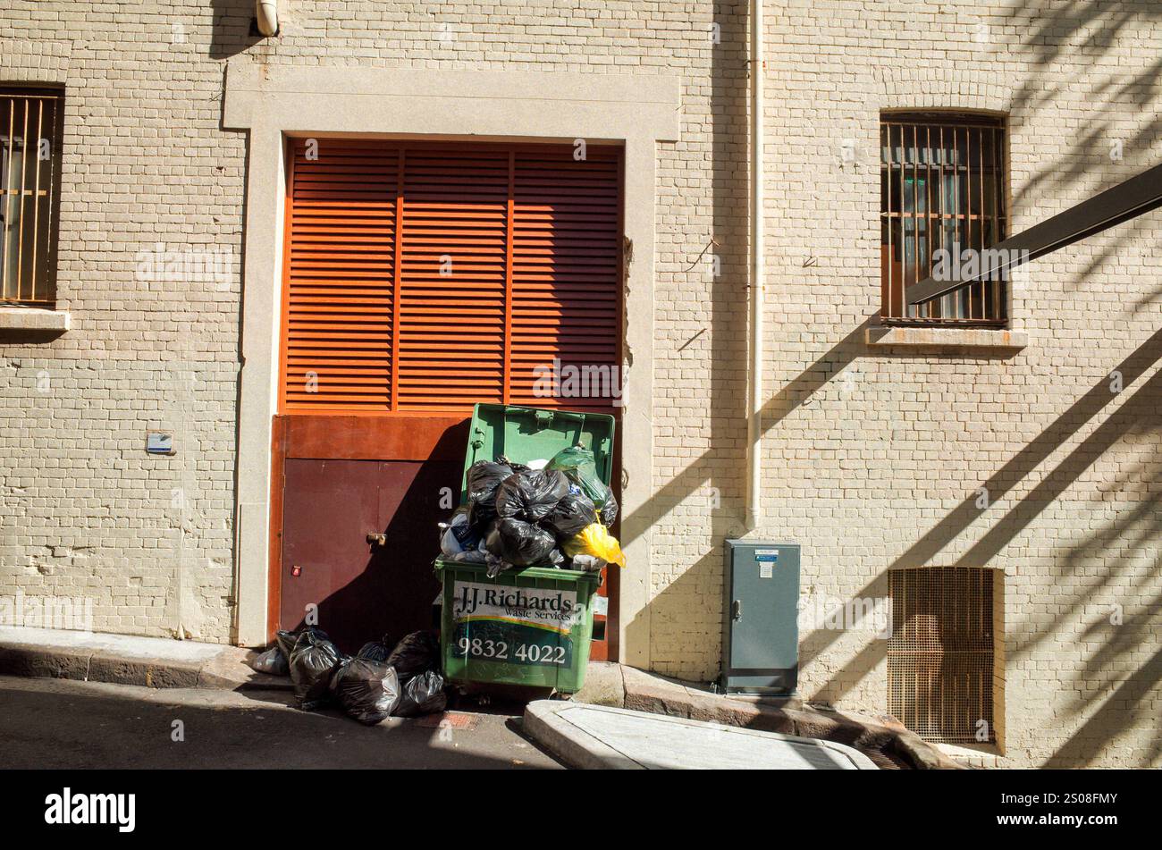 Editorial image of an overflowing garbage bin in an urban alley, set ...