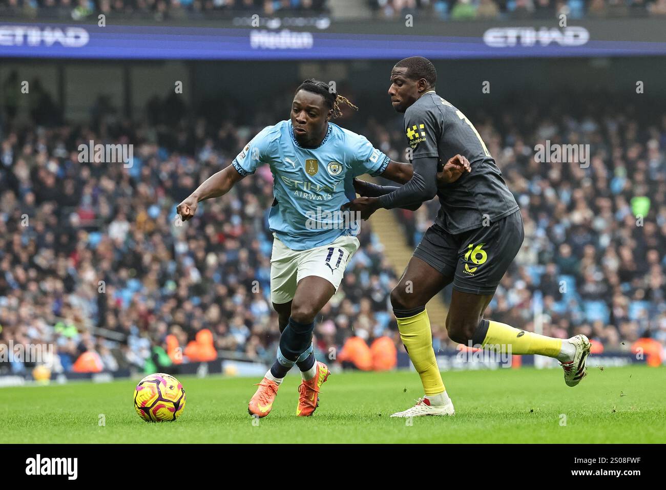 Jeremy Doku of Manchester City holds off Abdoulaye Doucouré of Everton ...