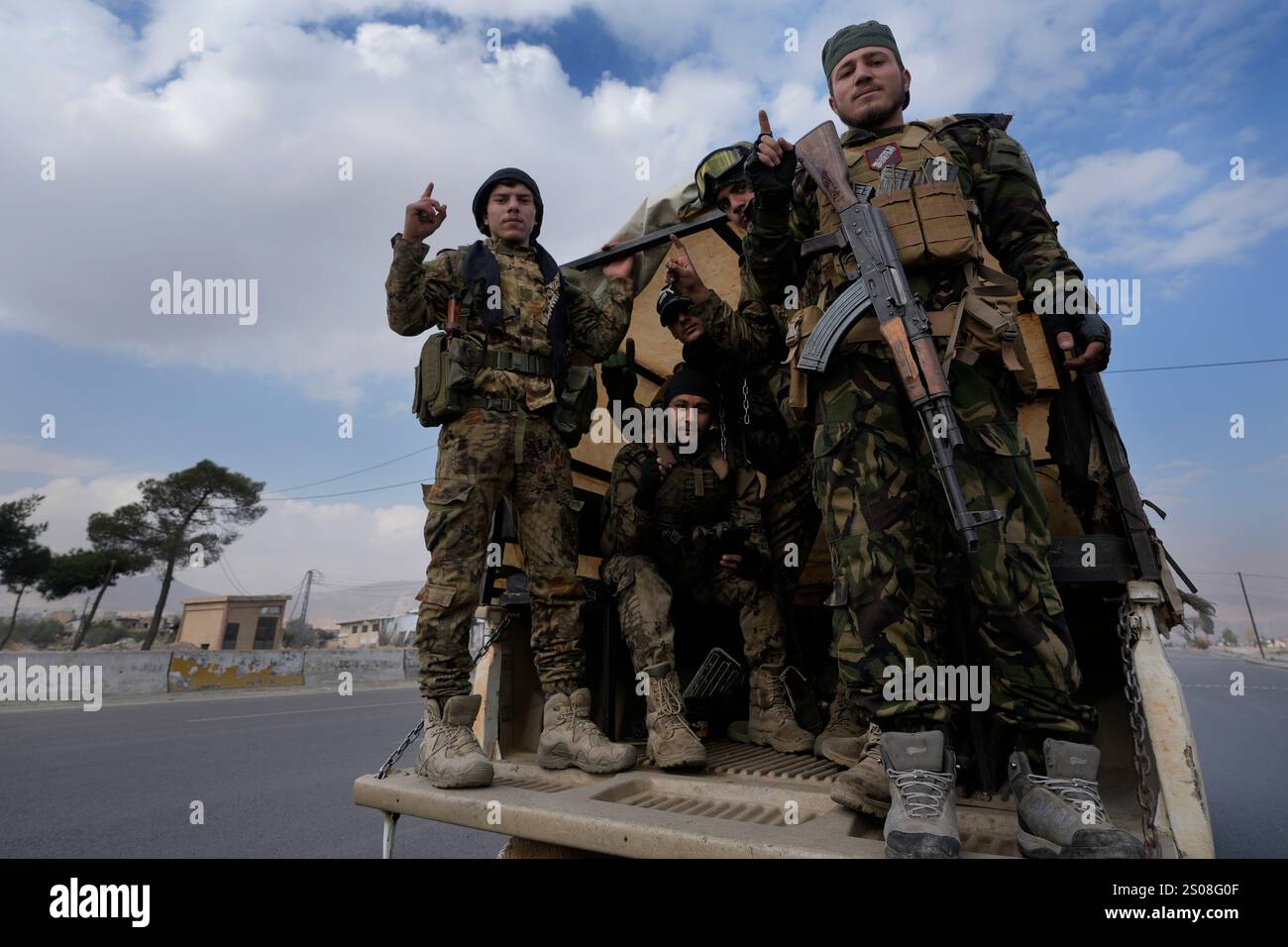 Syrian fighters stand on a vehicle, as they patrol at a highway, in ...