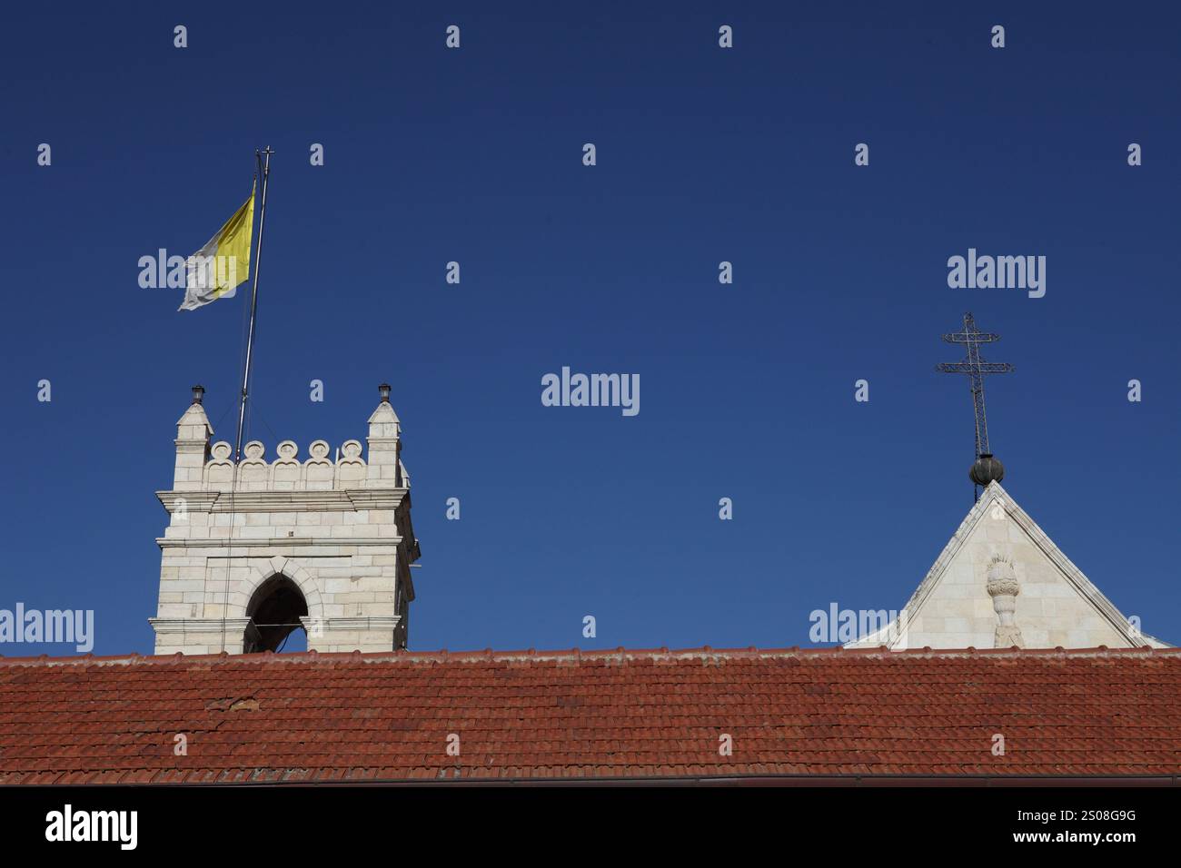 Yellow white flag of the Vatican flying over a tower on the roof the ...