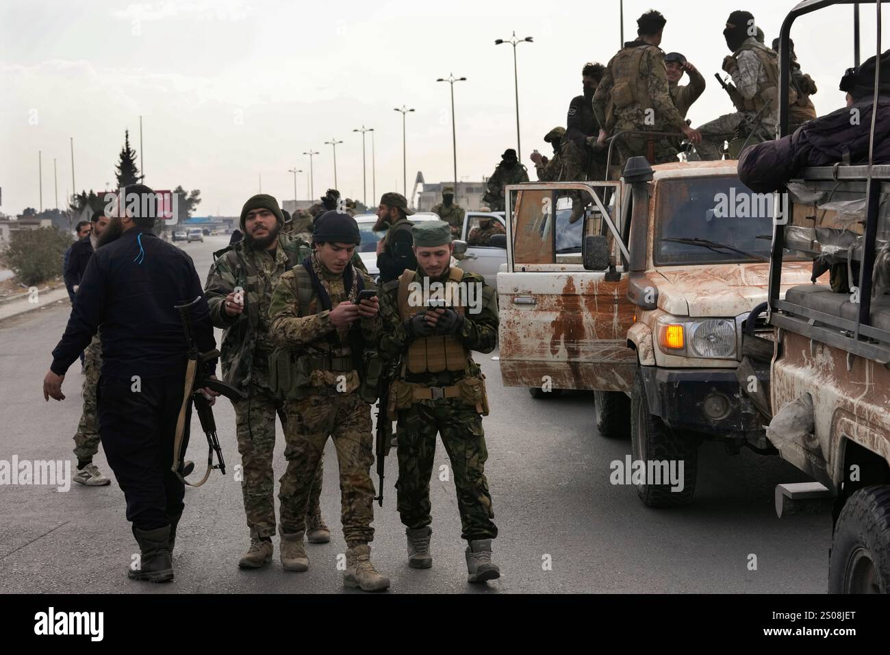 Syrian fighters check their mobiles, as they patrol a highway in ...