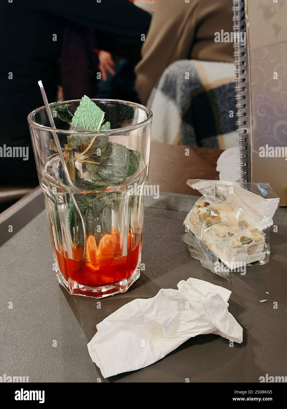 Glass with remnants of fruit mint tea and nougat on tray, casual scene ...