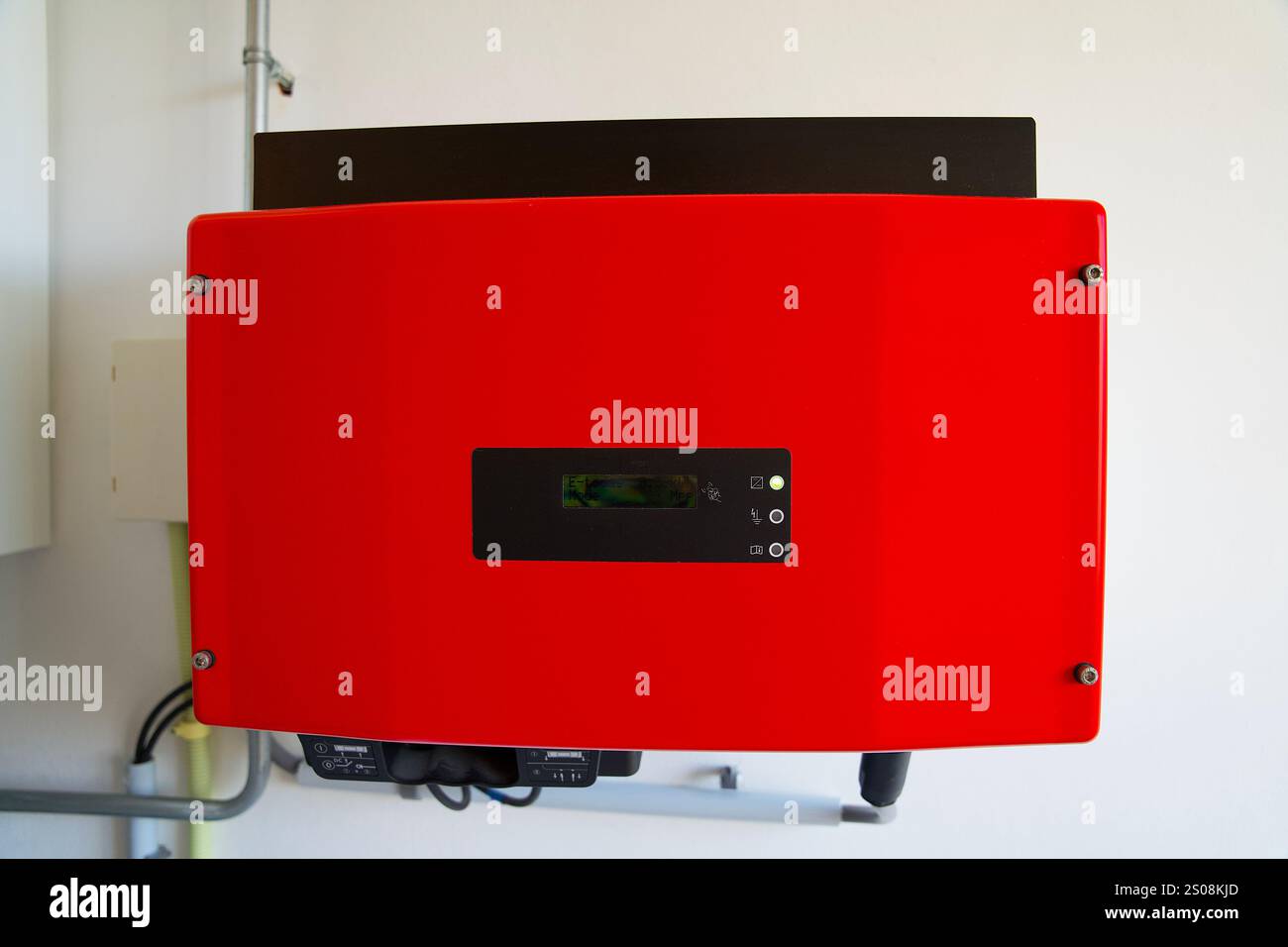 Close up of a red solar power inverter mounted to a white wall. Red ...