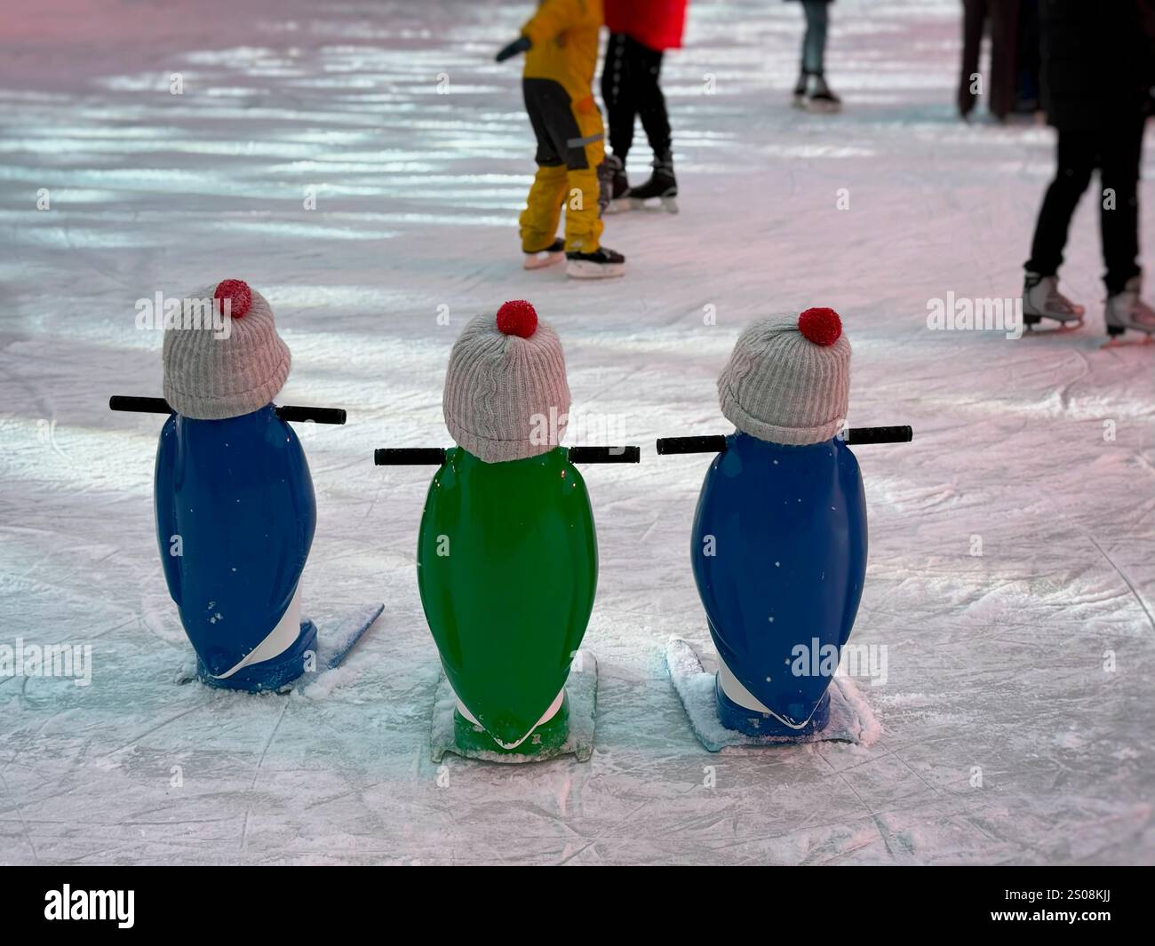 Colorful skating penguin in winter hats on ice rink. Fun activity for ...