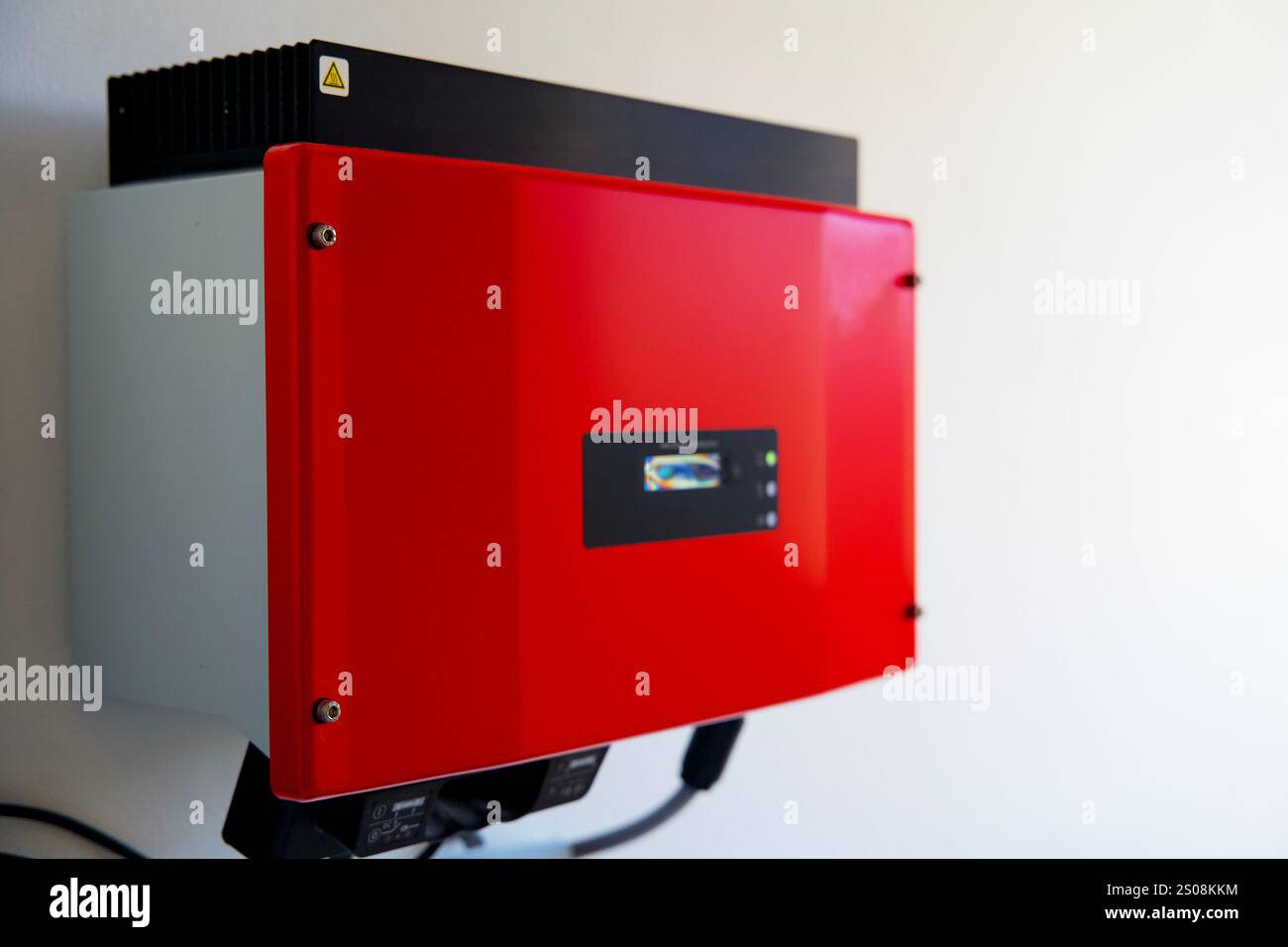 Close up of a red solar power inverter mounted to a white wall. Red ...